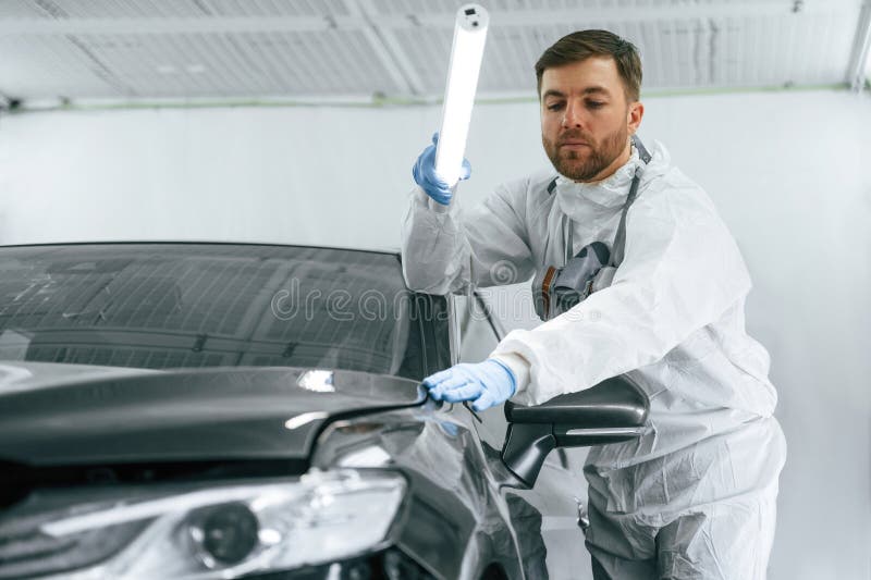 Front View. Garage Worker is Holding Lighting and Checking Surface of ...
