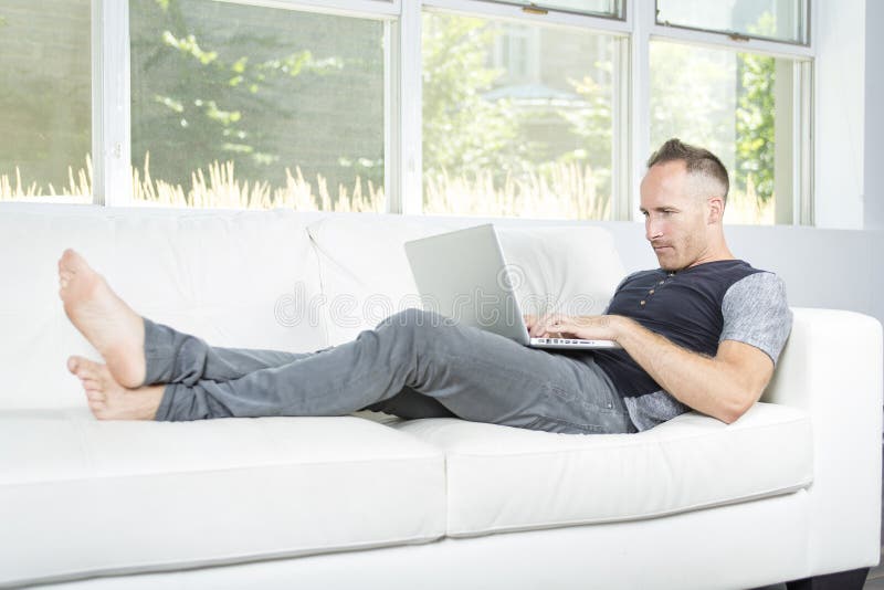Front View of a Handsome Man Using Laptop Sitting on Couch at Home ...
