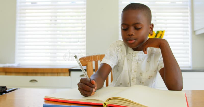 Front View of Little Black Boy Doing Homework at Dining Table in a ...
