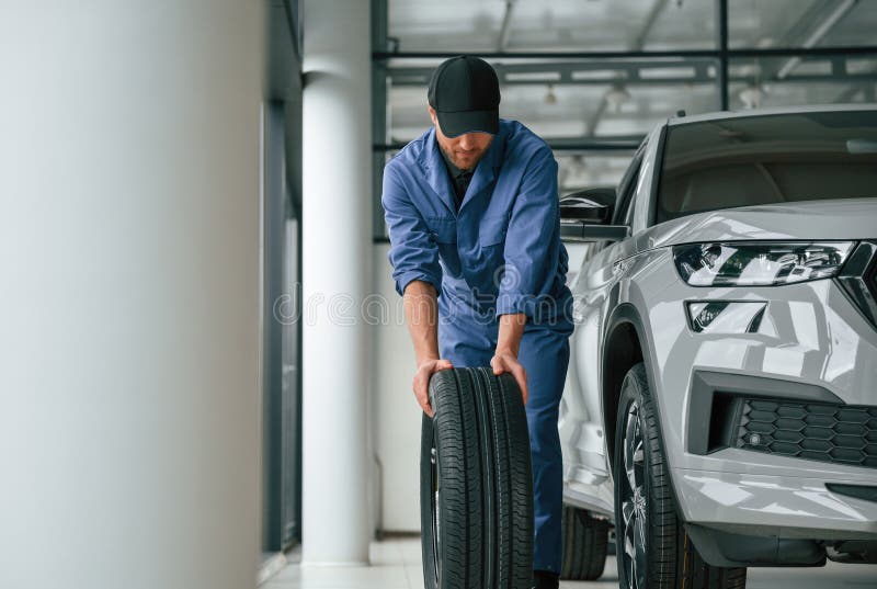 Front View, Moving the Tire. Man in Blue Uniform is Working in the Car ...