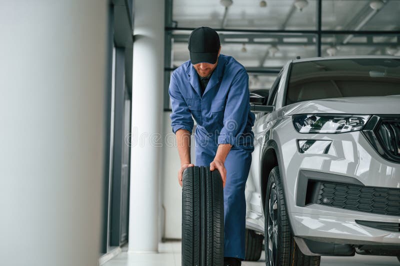 Front View, Moving the Tire. Man in Blue Uniform is Working in the Car ...