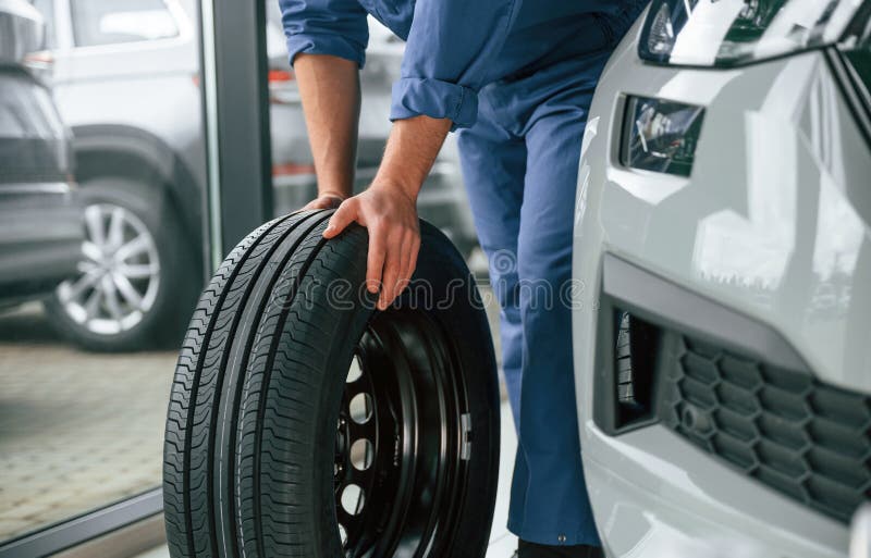 Front View, Moving the Tire. Man in Blue Uniform is Working in the Car ...