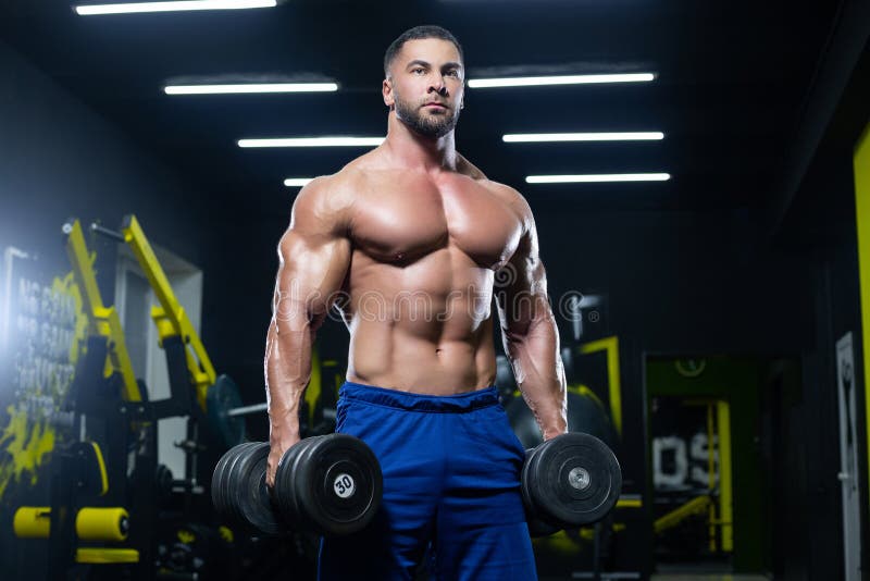 Front View Of A Muscular Bodybuilder Posing With Dumbbells In Blue ...