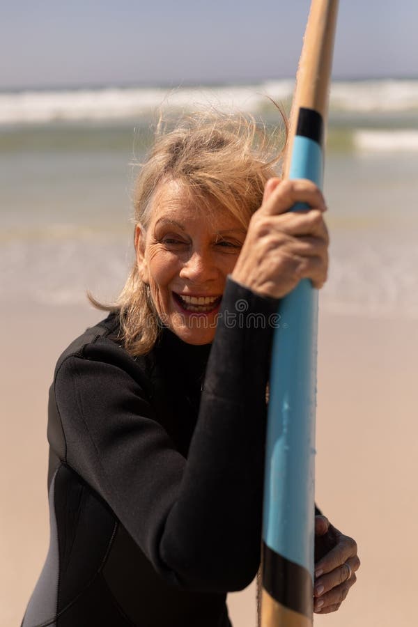 Front View of Senior Female Surfer Standing with Surfboard on the Beach ...