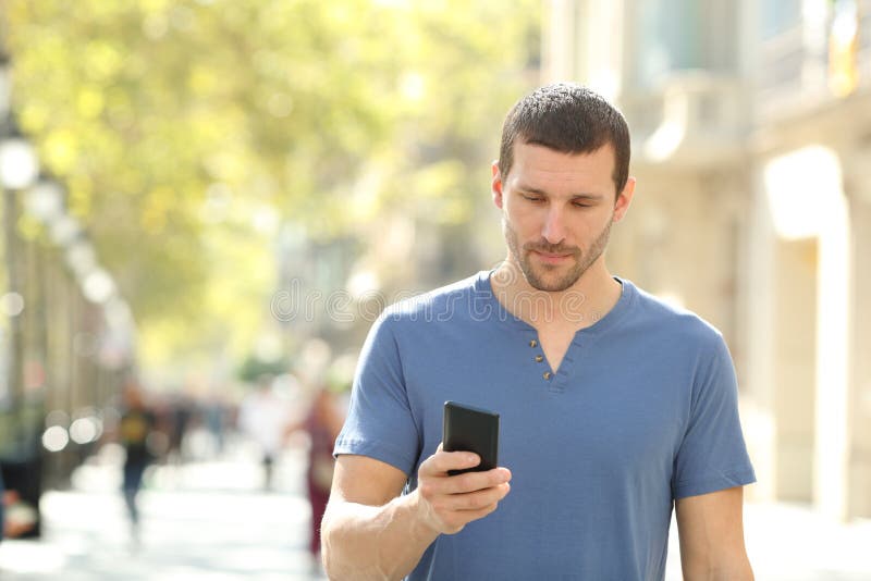 Guy Walking and Using a Smart Phone with Headphones Stock Image - Image ...