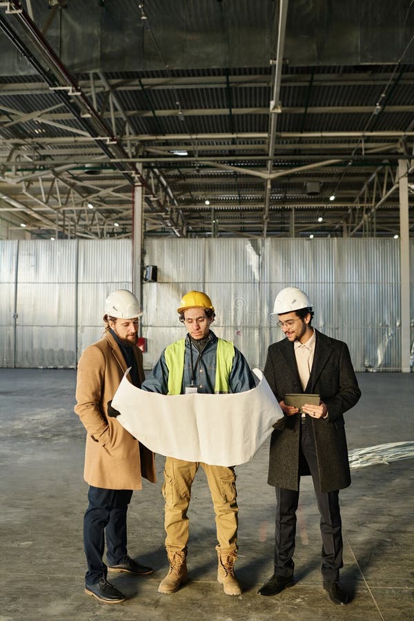Two Young Multiethnic Engineers Looking at Building Plan on Blueprint ...