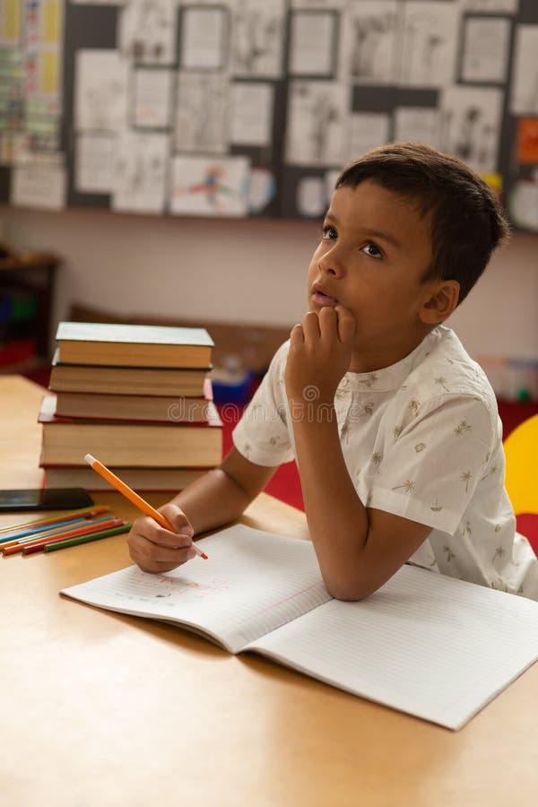 Thoughtful Schoolboy Studying at Desk in a Classroom Stock Photo ...