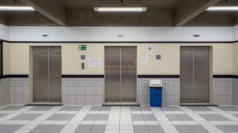 Front View of Three Elevators in Concrete Building with Blue Trash Bin ...