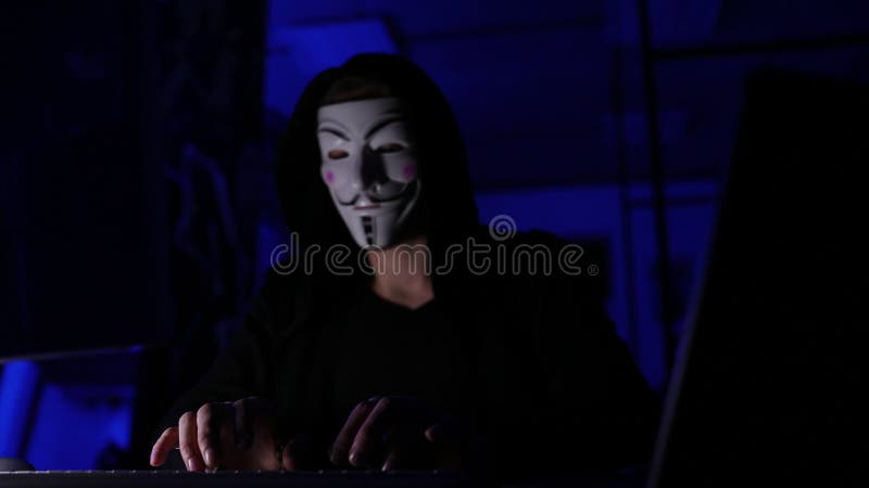 Front View Of Unrecognizable Hacker Man Wearing Anonymous Mask Typing On Wireless Keyboard