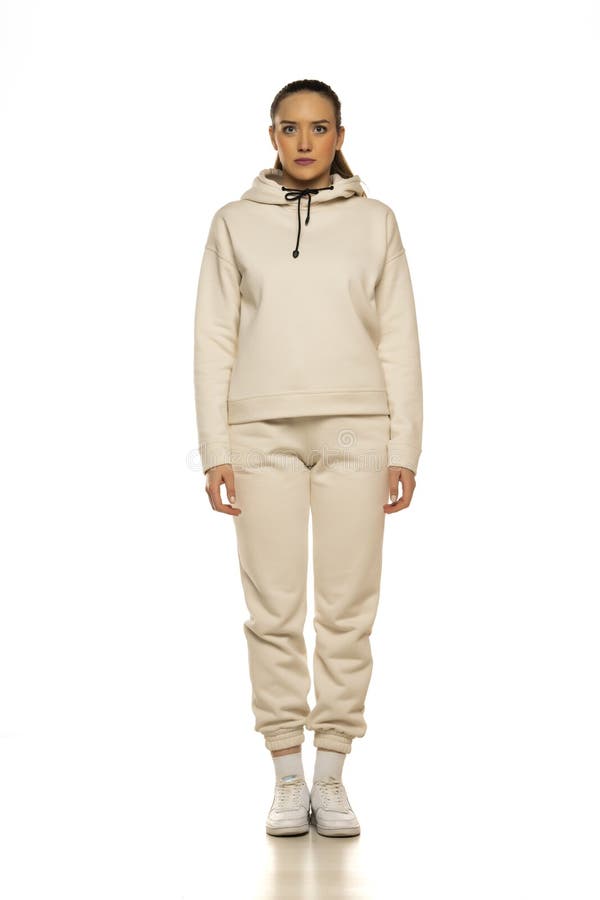 Front View of a Young Woman in a Beige Tracksuit Posing To a White ...
