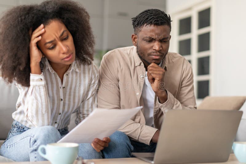 Frowning African American Married Couple Using Laptop Doing Paperwork ... Frowning African American Married Couple Using Laptop Doing Paperwork ...