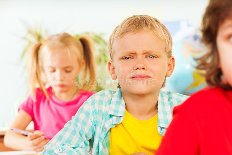 Frowning Boy Looking Straight in Classroom Foto de archivo - Imagen de ...