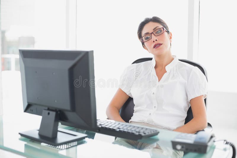 Frowning Businesswoman Sitting at Her Desk Looking at Computer Stock ...