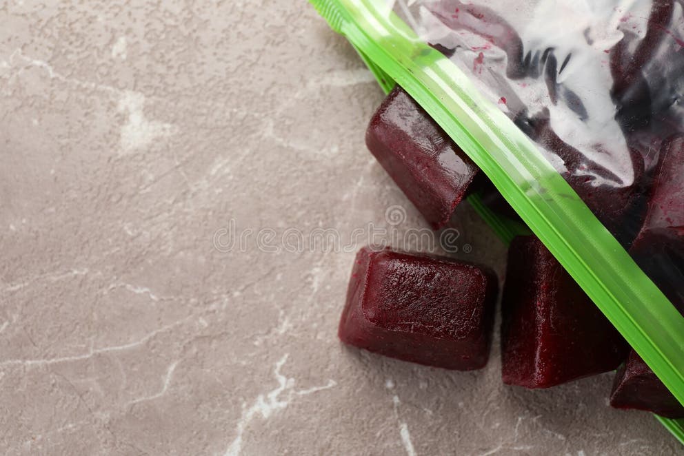 Frozen Beet Puree Cubes in Plastic Bag on Marble Table, Top View. Space ...