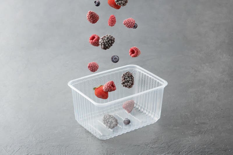 Frozen Berries Fall into a Plastic Box on a Grey Concrete Background ...