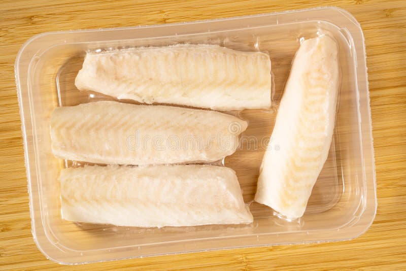 Frozen Cod Fish Loins in Vacuum Package on the Cutting Board. Top View ...