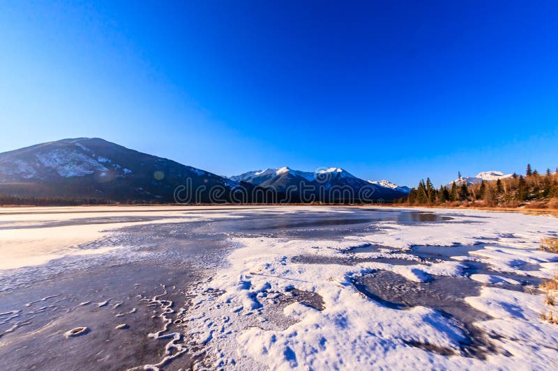 A Frozen Lake with Snow on the Mountains in the Background Stock Photo ...