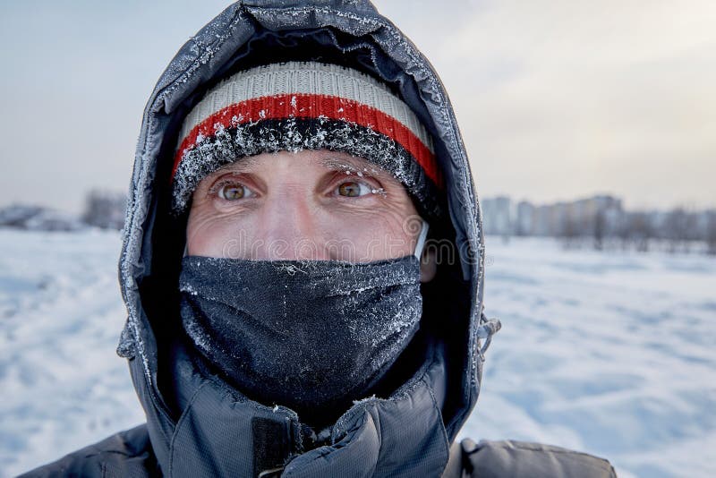 A Frozen Man in a Mask in Winter Clothes is Standing Outside, it S Cold ...