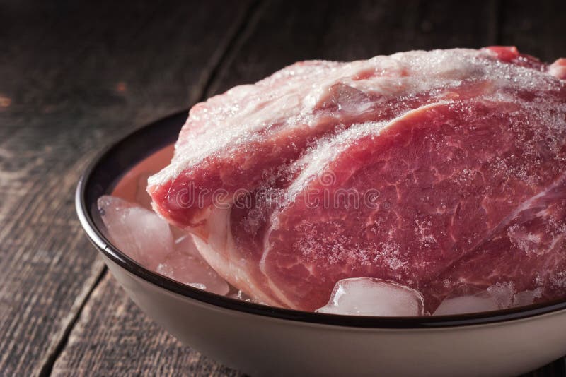 Frozen Pork on the Plate with Ice on the Wooden Table Stock Photo ...
