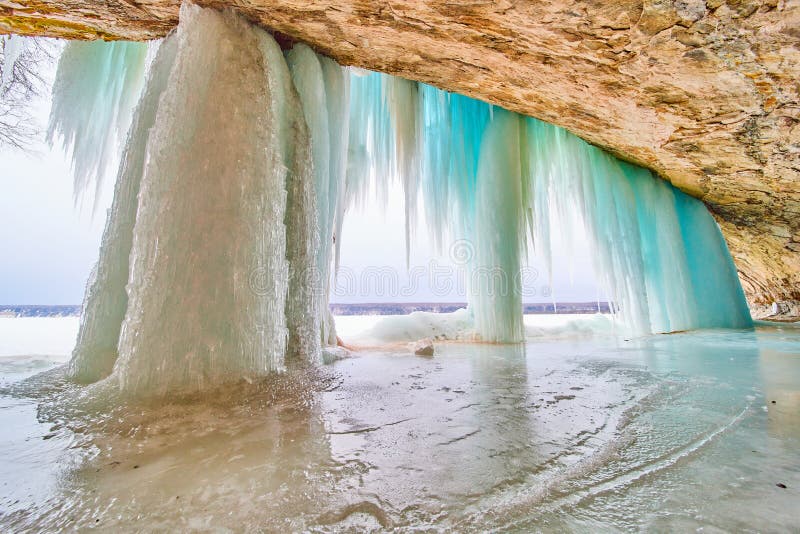 Frozen Waterfall on Lake Inside Cave Opening with Blue Icicles Stock ...
