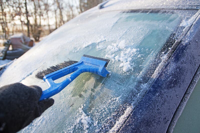 Frozen windshield from a car and a hand scraping the ice with an ...