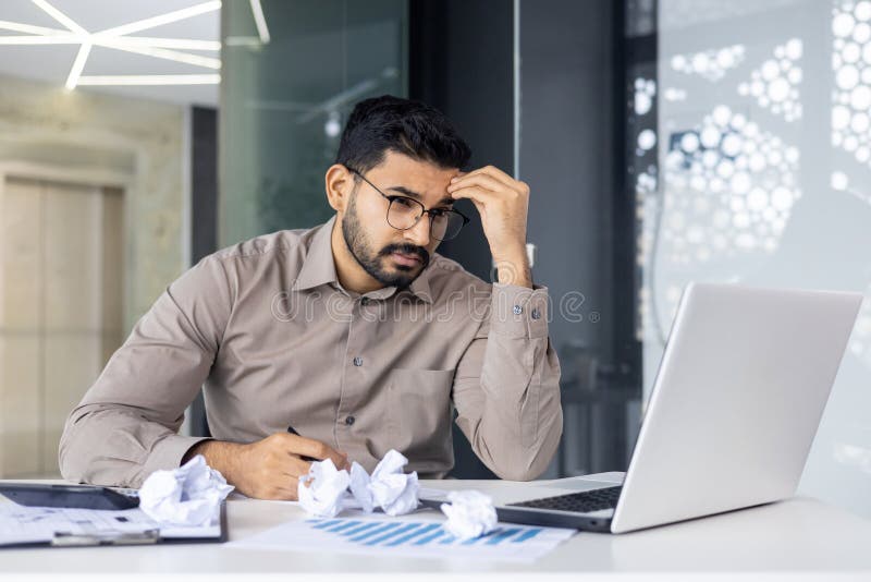 Frustrated Businessman Sitting at Desk with Crumpled Papers, Analyzing ...