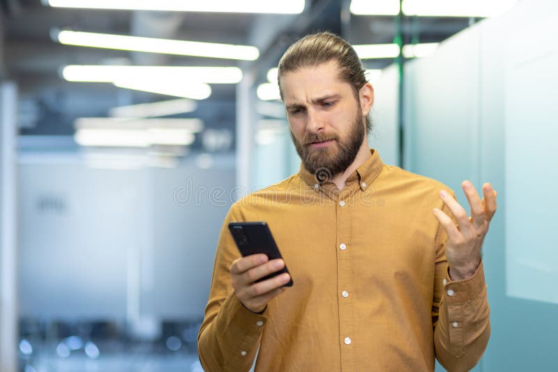 Frustrated Man Looking at Smartphone with Disappointment in a Modern ...