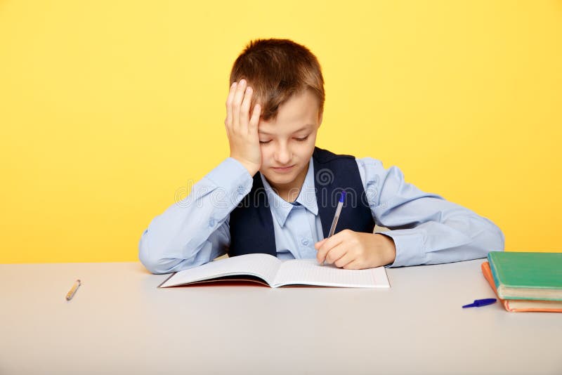 Frustrated Upset Boy at School Sitting at the Desk and Dotng Classwork ...