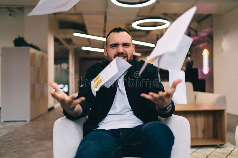 Frustrated Young Man Sitting in Sofa and Throwing Papers in Air Stock ...