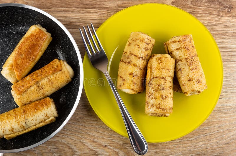 Frying Pan with Pancake, Fried Pancake Rolls and Fork in Plate on Table ...