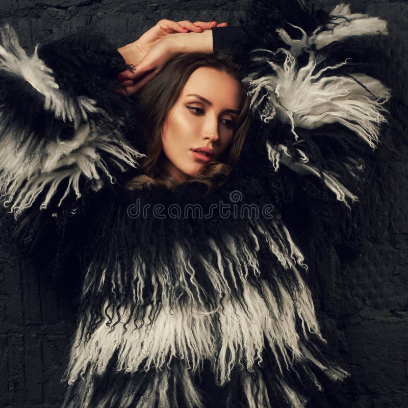 Elegant Female Model In Faux Fur Coat Posing Against Gray Brick Stock