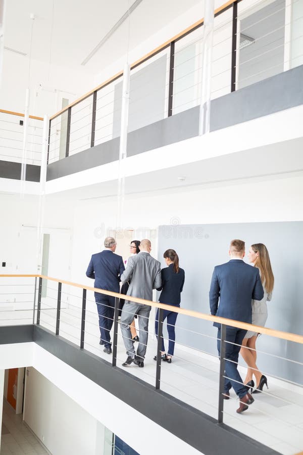 Business People Walking by Railing on Corridor in Office Stock Photo ...