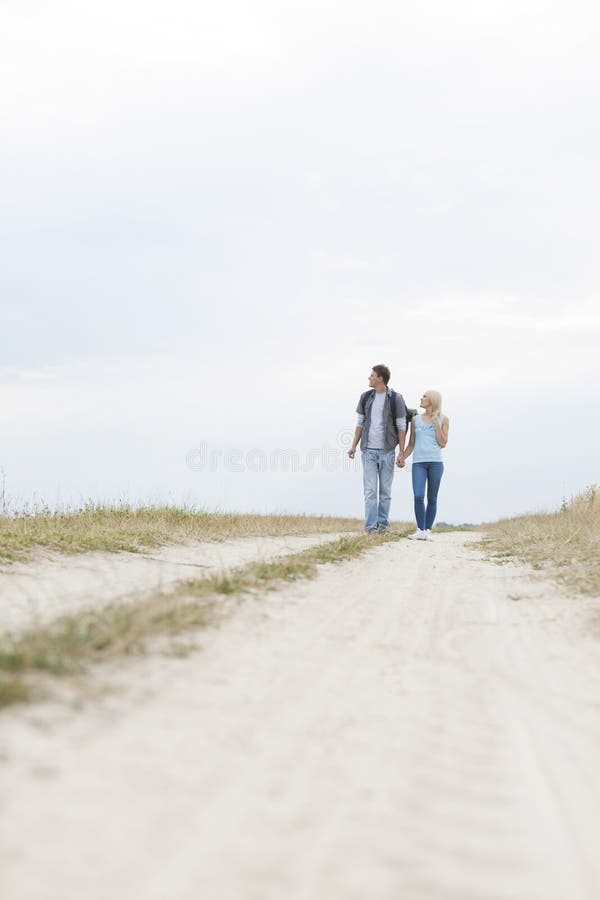 Full Length Of Young Hiking Couple Walking On Path At Field Stock Photo ...