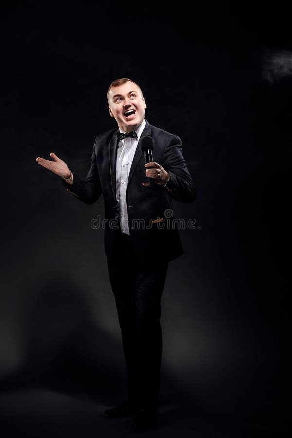 Full Length of Young Man in Costume with Microphone on Black Background ...
