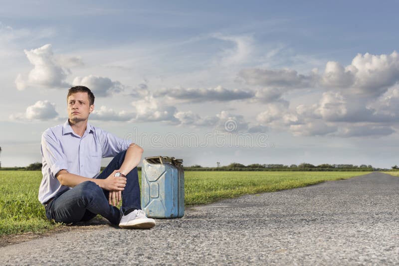 Full Length Of Young Man With Empty Gas Can Sitting By Country Road