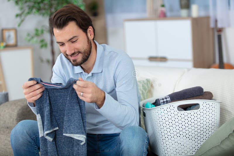 Full Length Young Man Folding Laundry on Sofa Stock Image - Image of ...