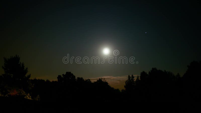 The Full Moon Moves Slowly Across the Night Sky. Sparse Clouds Float ...