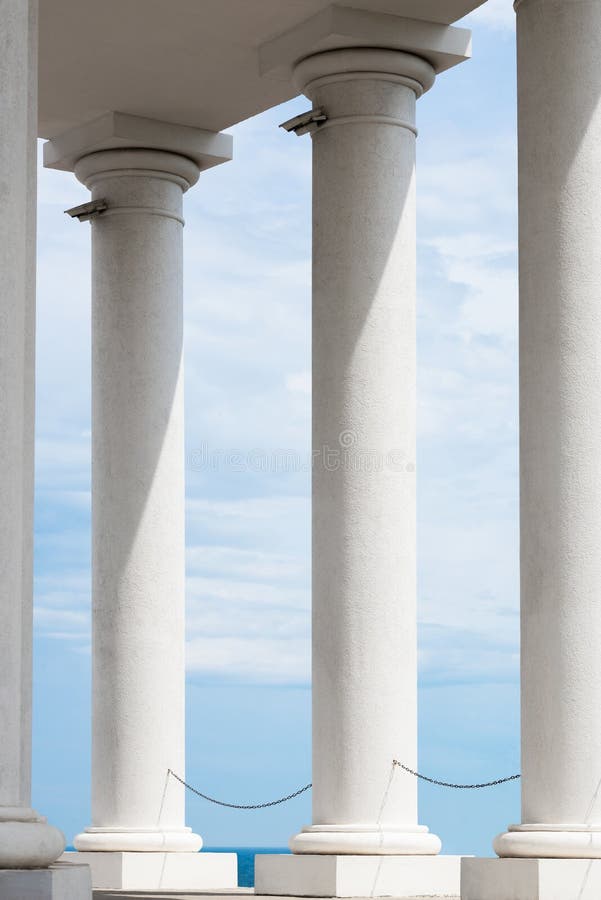 A Row of Huge White Columns with a Sky in the Clouds in the Background ...