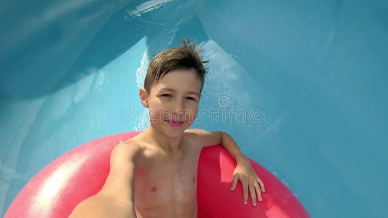 Funny Boy Goes Down on the Water Slide in the Water Park Looks into the ... Funny Boy Goes Down on the Water Slide in the Water Park Looks into the ...