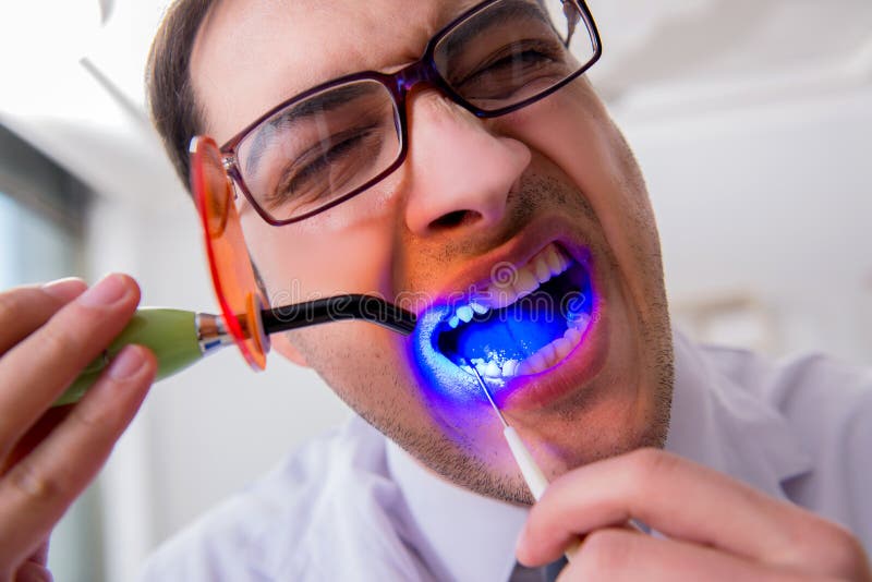 The Funny Dentist with Curing Light in Medical Concept Stock Image ...