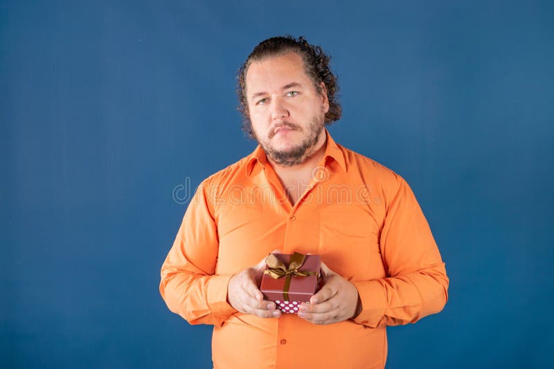 Funny Fat Man In Orange Shirt Opens A Box With A Gift Stock Photo ...