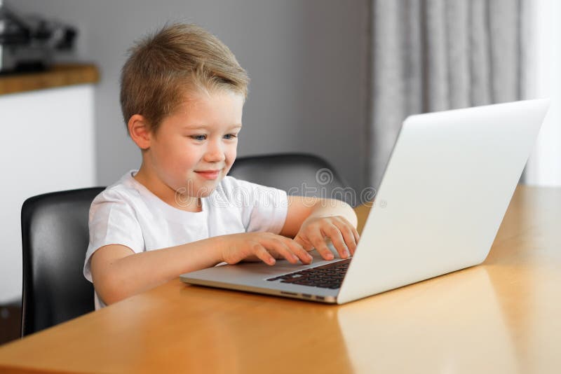 Funny Young Boy Using a Laptop Computer Sitting on Top of a Table at ...