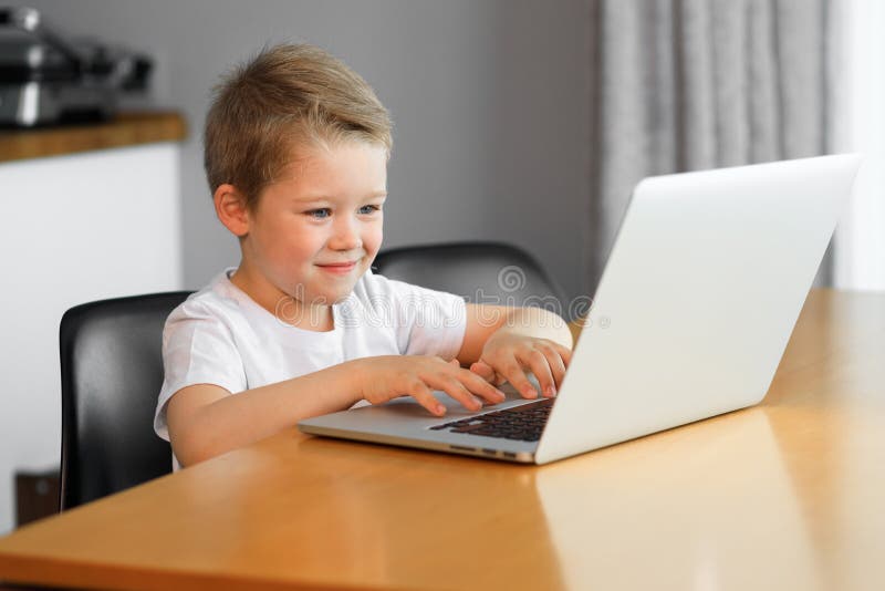Funny Young Boy Using a Laptop Computer Sitting on Top of a Table at ...