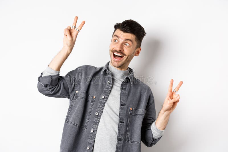 Funny Young Man Showing V-signs and Smiling at Left Side, Looking at ...
