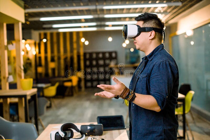 Future is Now. Handsome Young Chinese Man in VR Headset Gesturing and ...