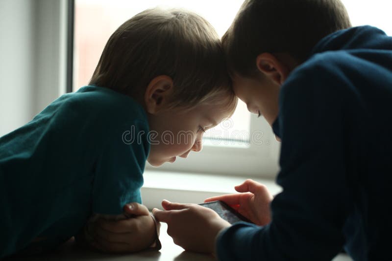 Game Addiction in Children Two Children Playing with a Smartphone while ...