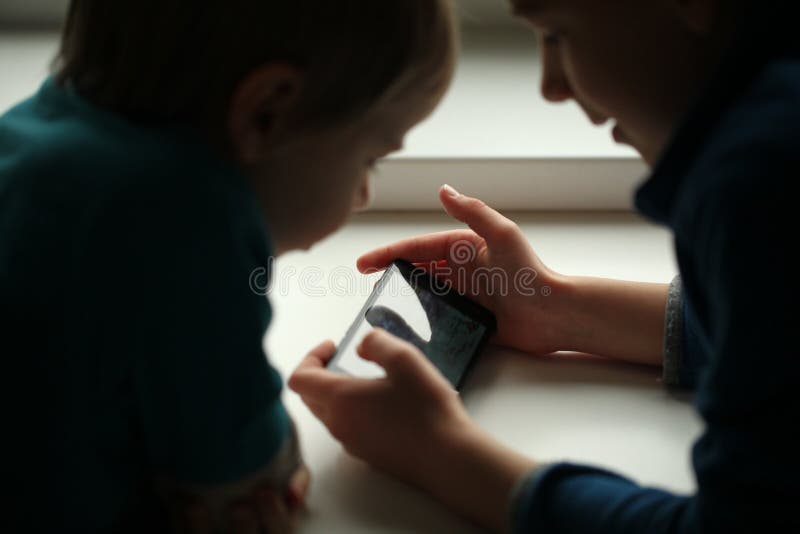 Game Addiction in Children Two Children Playing with a Smartphone while ...