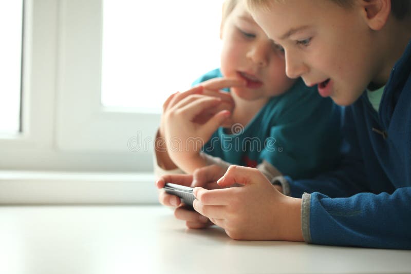 Game Addiction in Children Two Children Playing with a Smartphone while ...