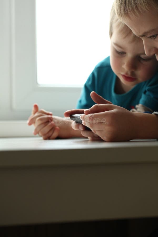 Game Addiction in Children Two Children Playing with a Smartphone while ...
