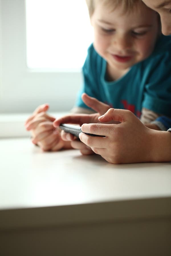 Game Addiction in Children Two Children Playing with a Smartphone while ...